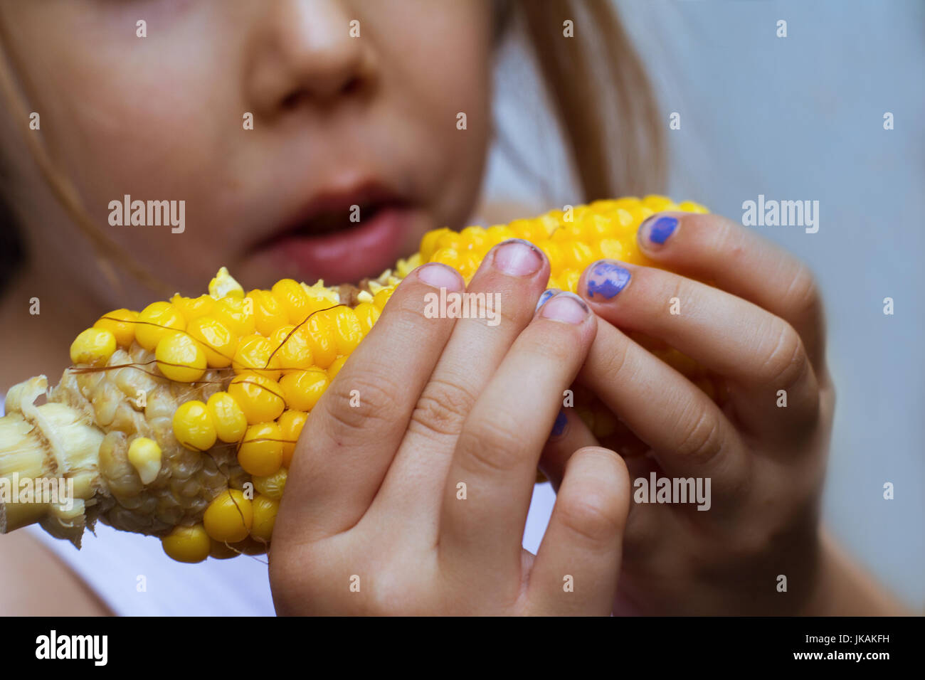 closeup of child with dirty hands eating a corn on the cob with ...