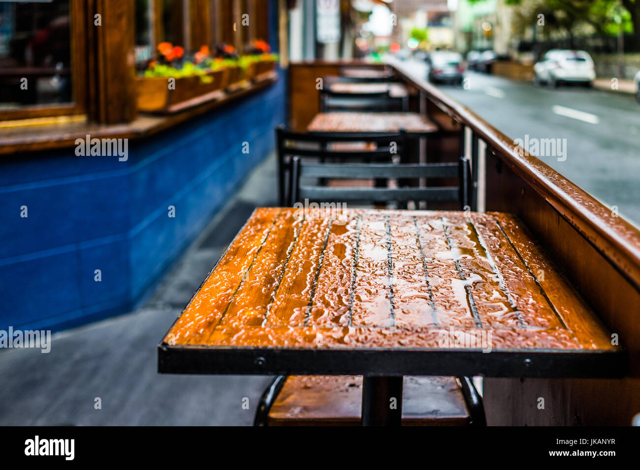 Wet tables closeup outside restaurant during heavy rain with street and ...