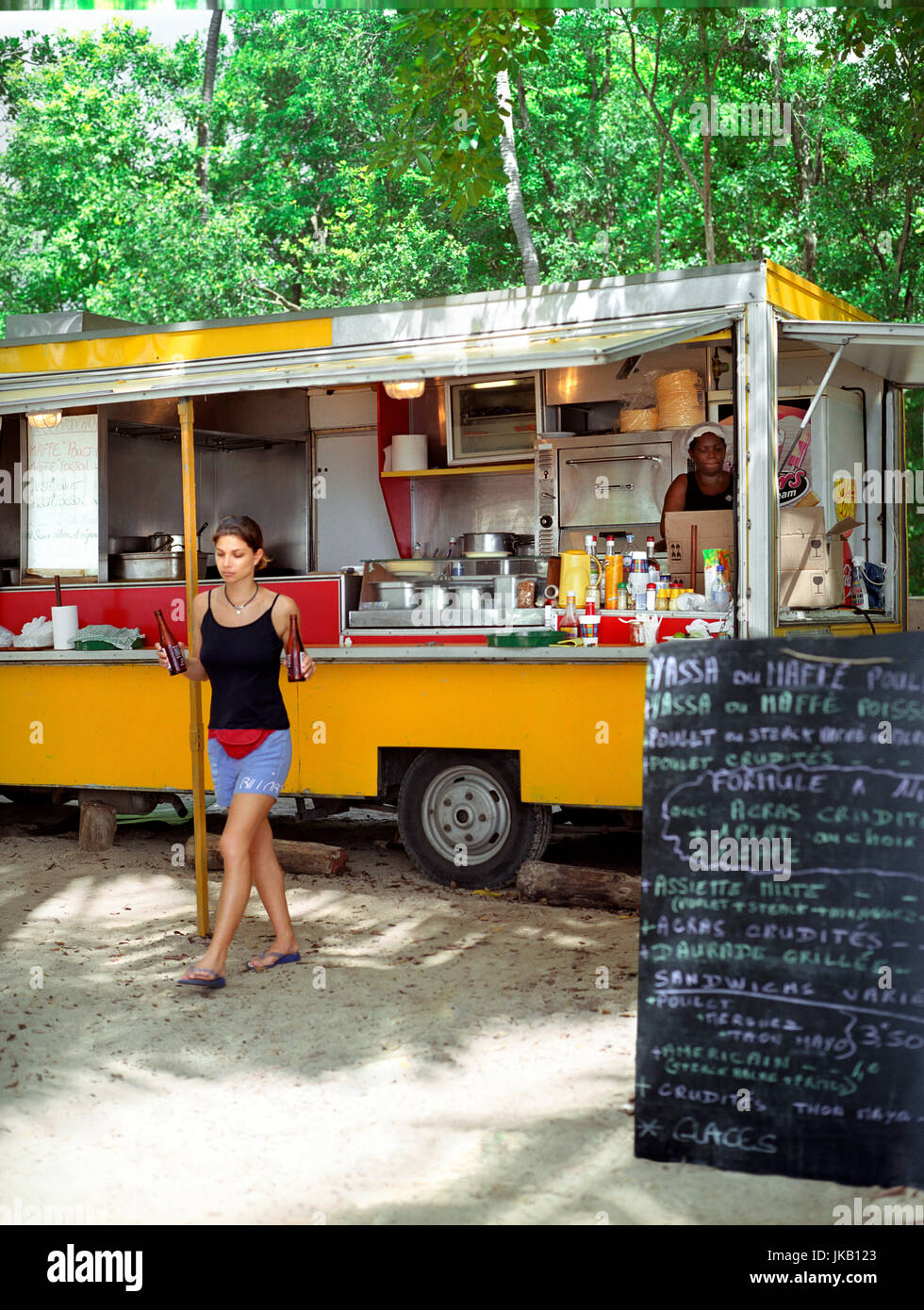 An attractive female tourist buys some beers from an beach side food ...