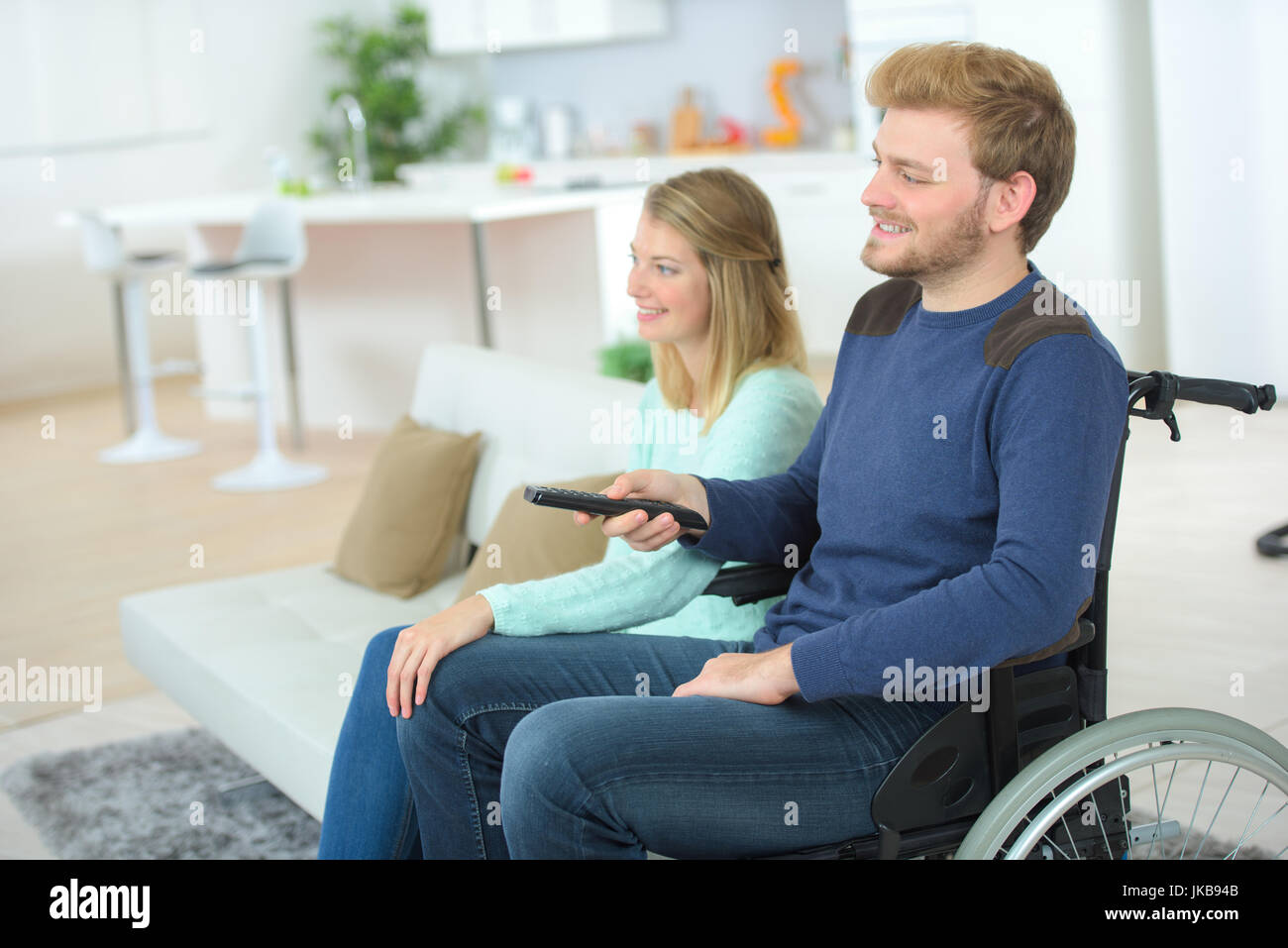 couple watching tv at home man sitting on wheelchair Stock Photo - Alamy
