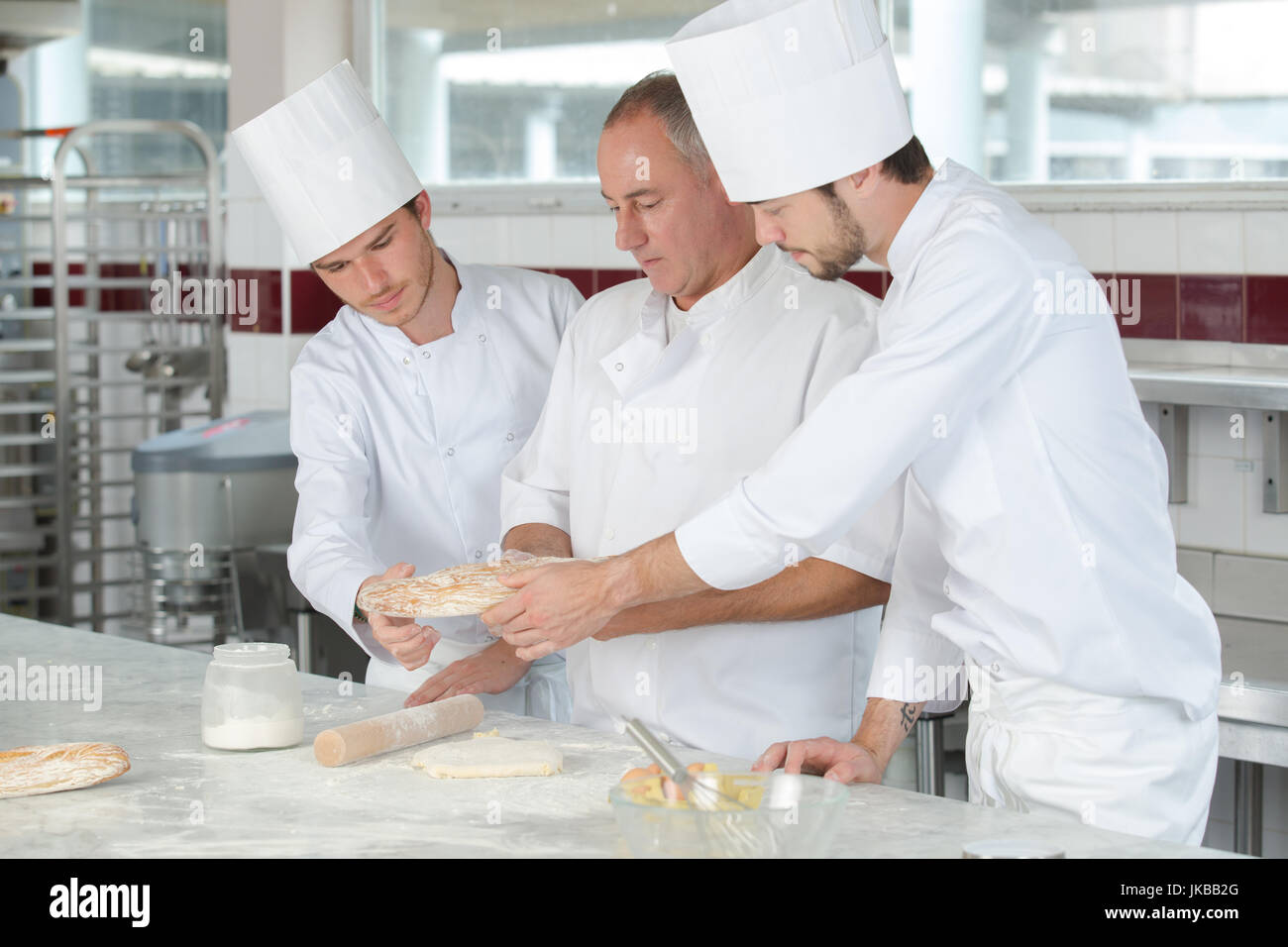 chef with 2 young cooks in kitchen preparing dish Stock Photo - Alamy