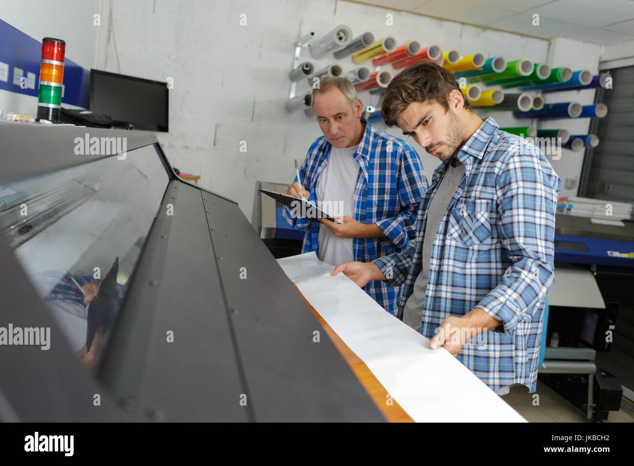 two men looking down at professional printer Stock Photo - Alamy