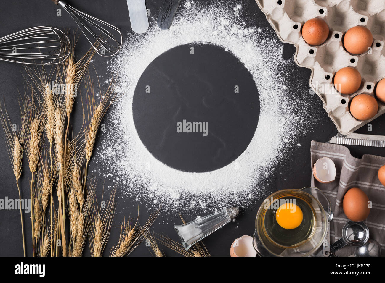 Baking utensils and ingredient with whisk egg on black background ...