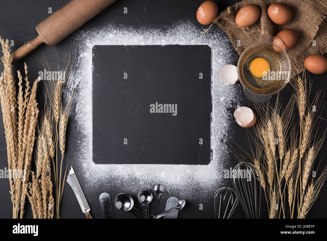 Baking utensils and ingredient with whisk egg on black background ...