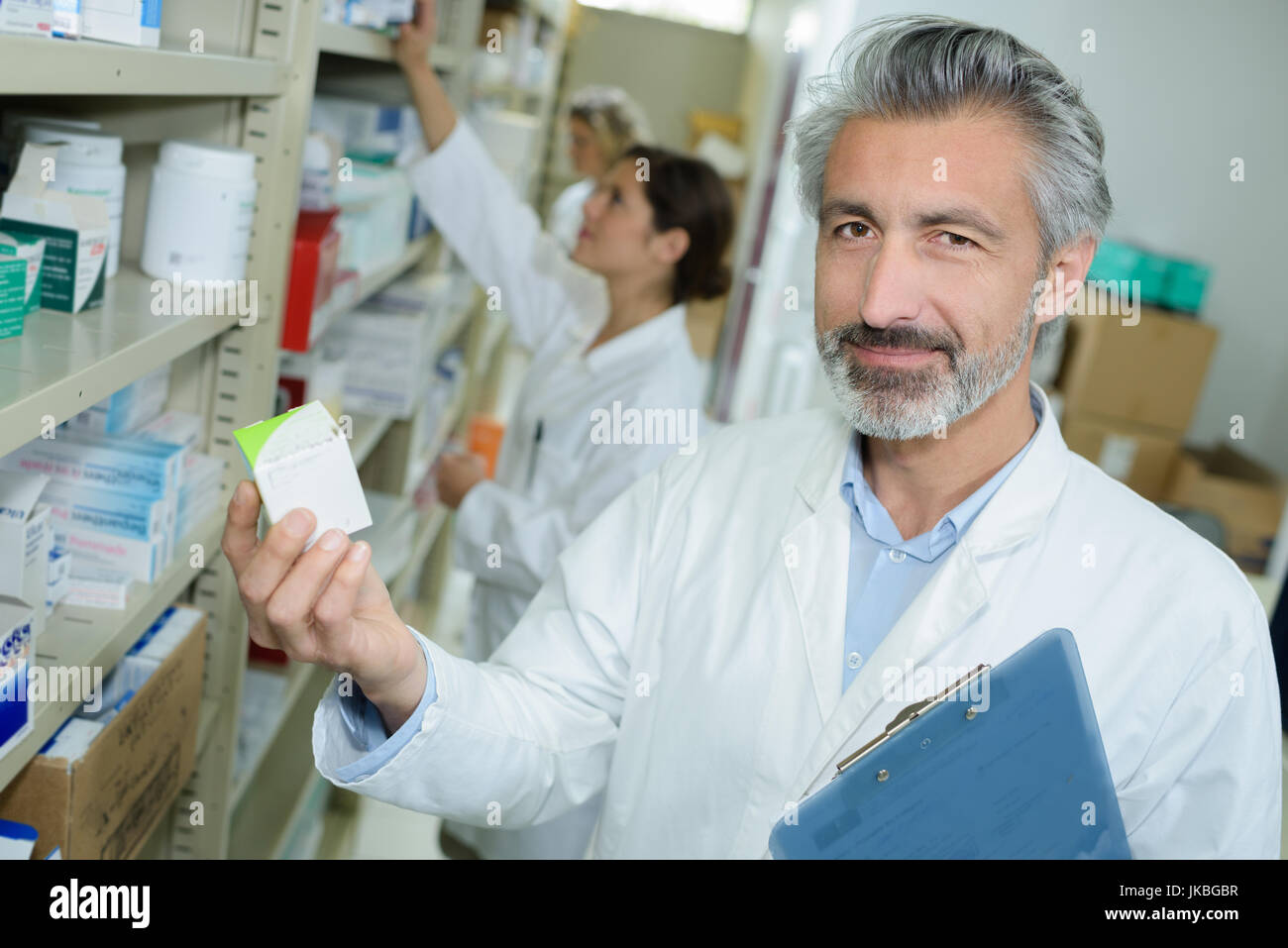 pharmacists standing at counter and showing medicine box in pharmacy ...