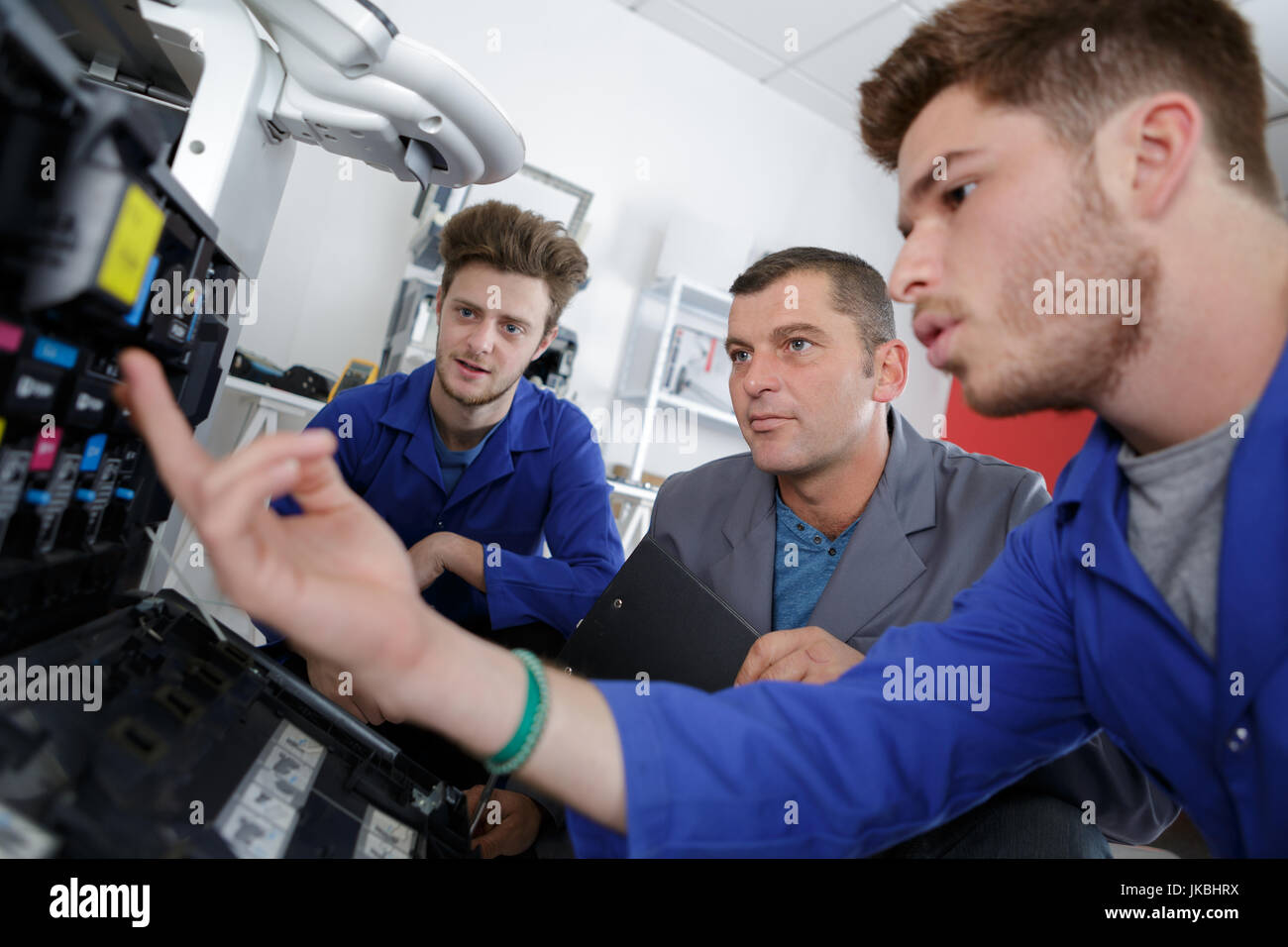 two apprentices and teacher working on printer Stock Photo - Alamy