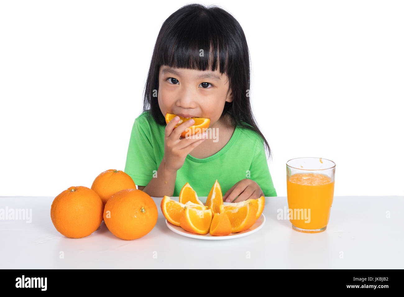 Happy Asian Chinese little girl eating orange in isolated white ...