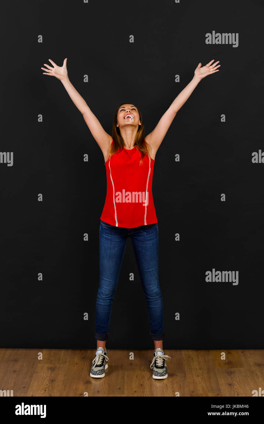 Beautiful happy woman with arms open in front of a black wall Stock ...
