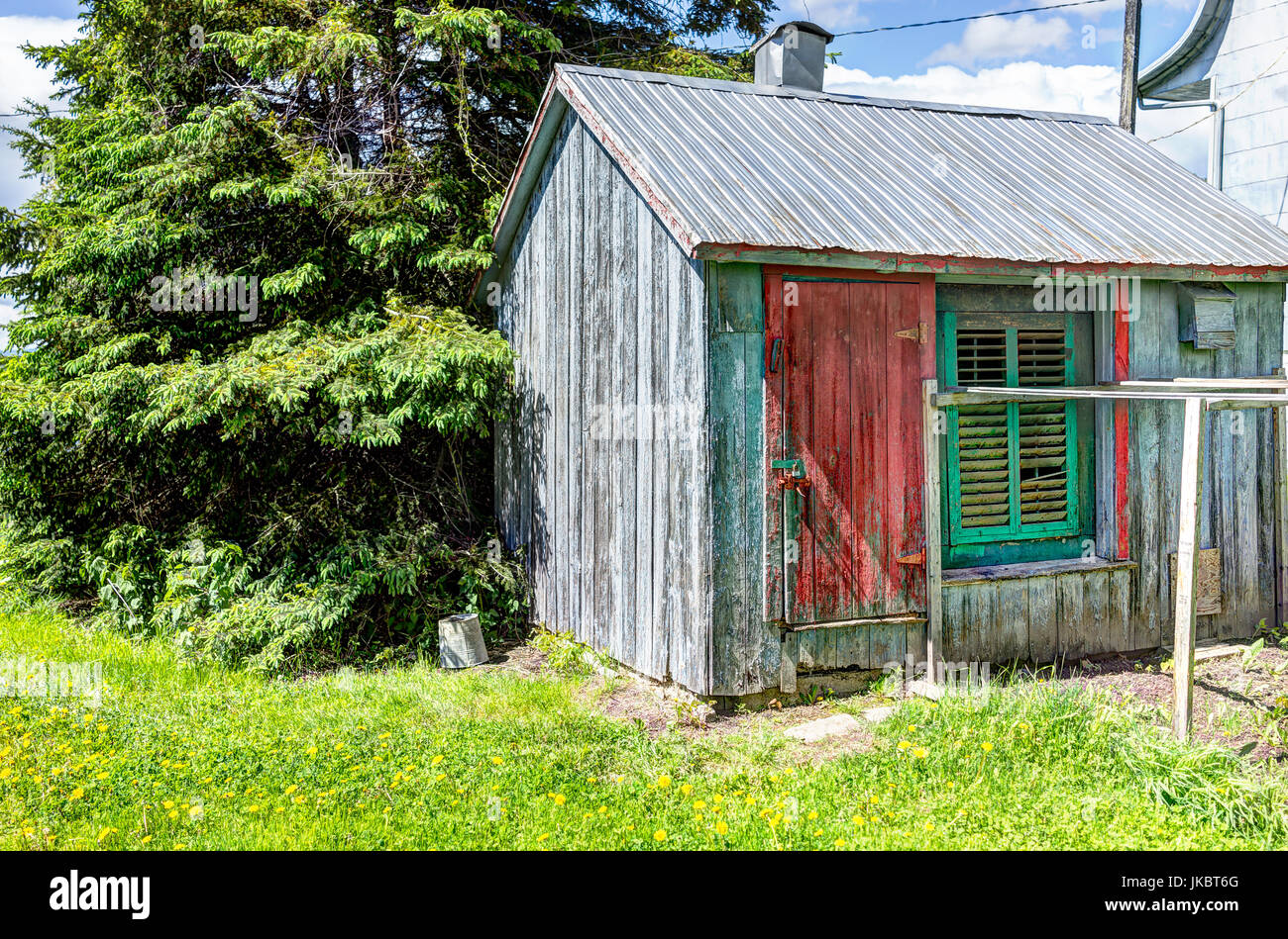 Green and red painted old vintage barn shed in summer landscape field ...