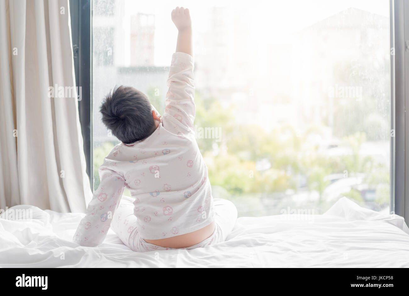 obese fat boy in pajamas is sitting on bed stretching.Good morning ...