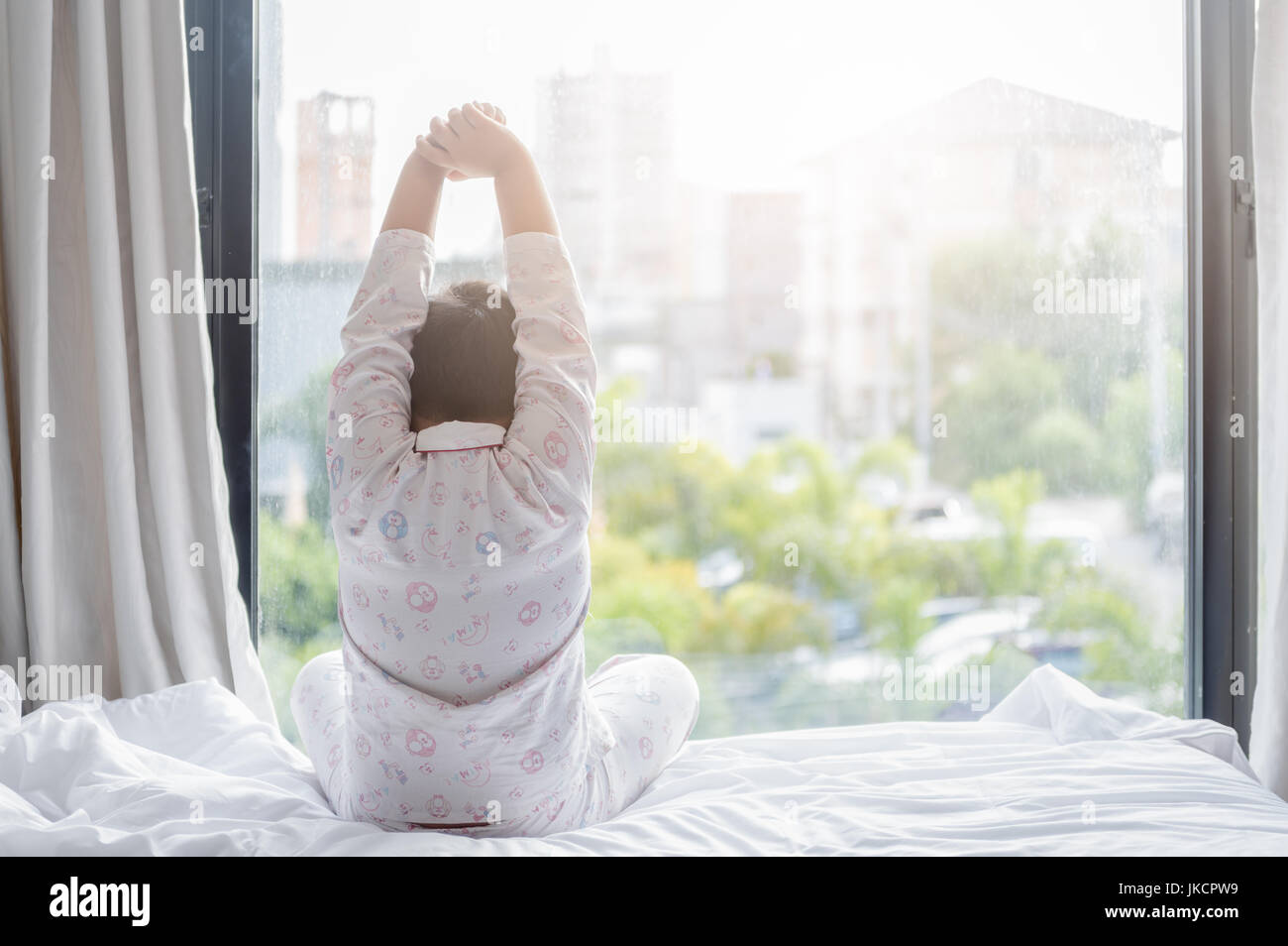 obese fat boy in pajamas is sitting on bed stretching.Good morning ...