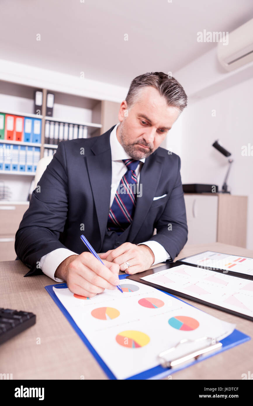 Adult businessman writing on charts Stock Photo - Alamy