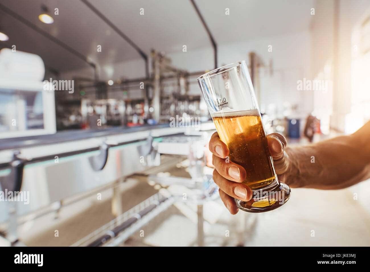 Close up of brewer testing beer at brewery factory. Man hand holding a ...