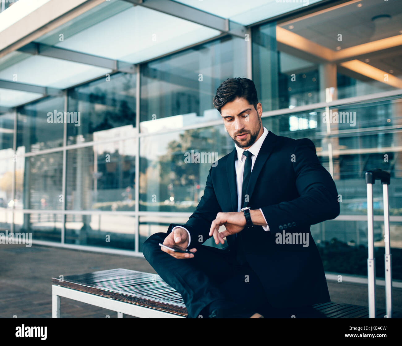 Young businessman waiting and checking time with mobile phone. Business ...