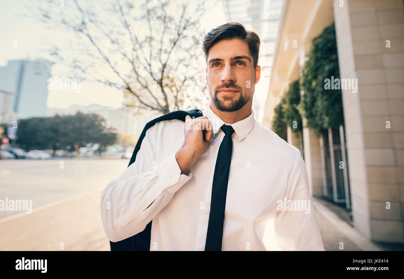 Portrait of handsome young man in formal wear walking outside on the ...