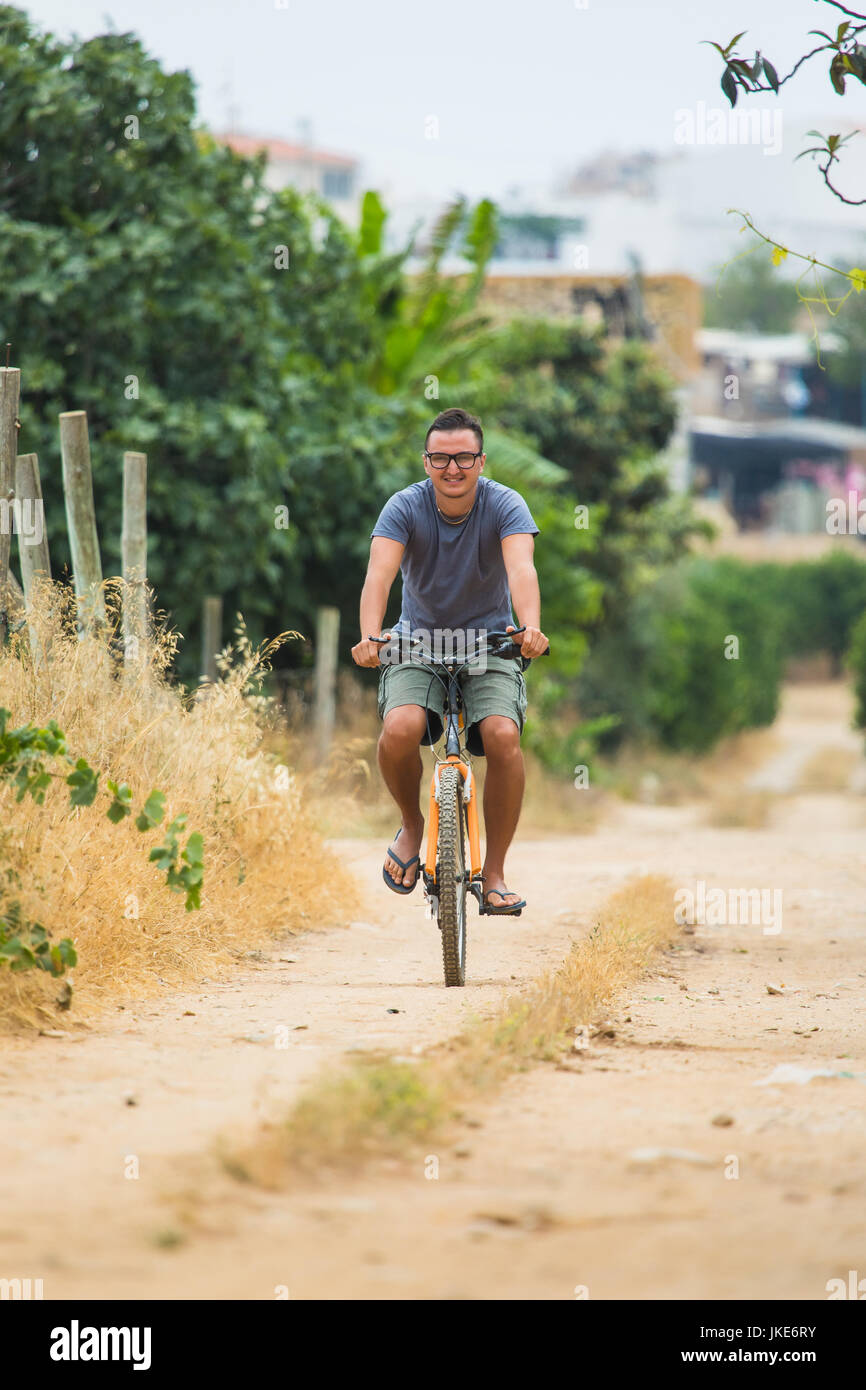 Portrait of happy guy riding bicycle in the park Stock Photo - Alamy