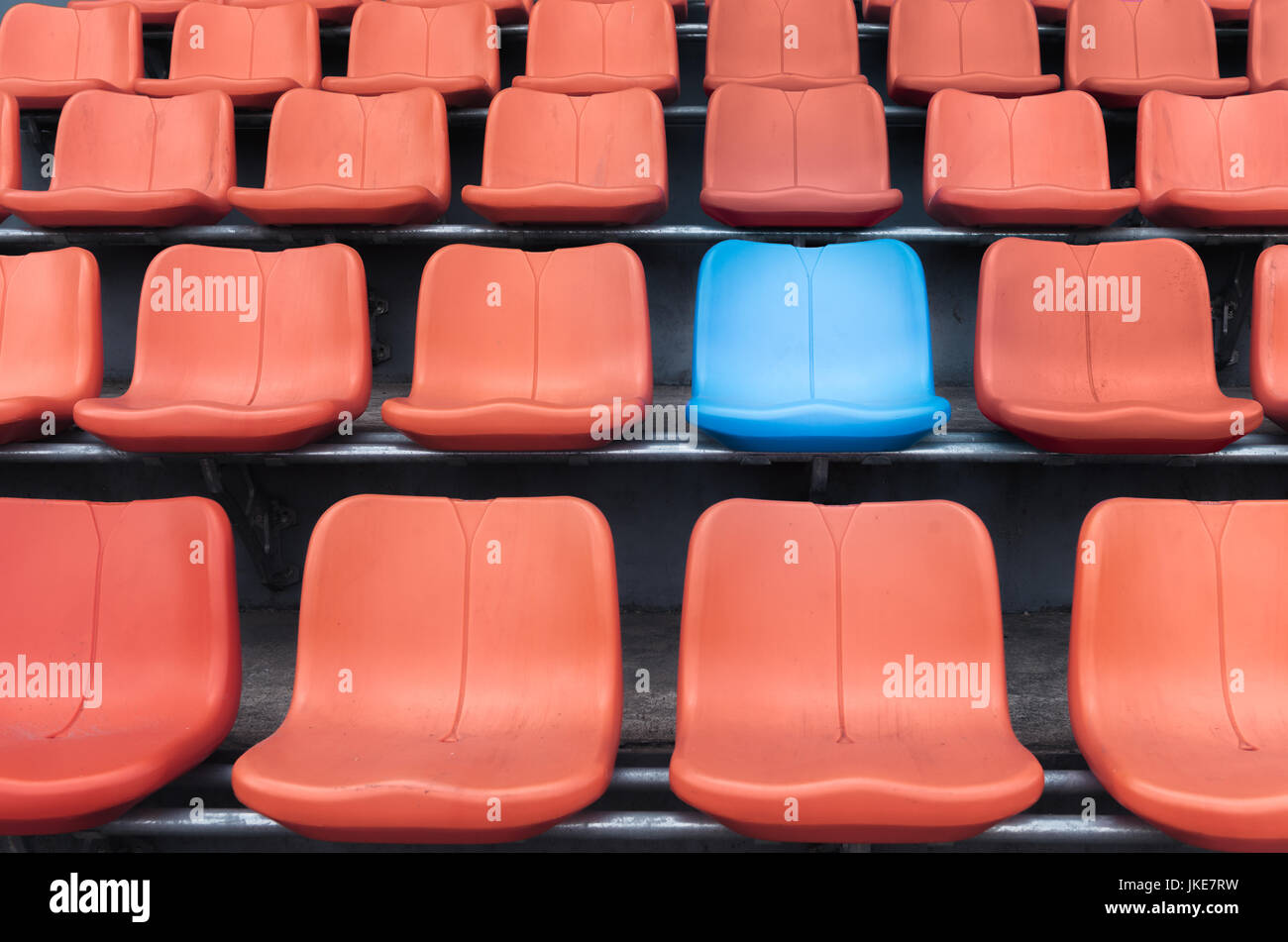 A blue chair amidst rows of orange plastic spectator seats, competition ...