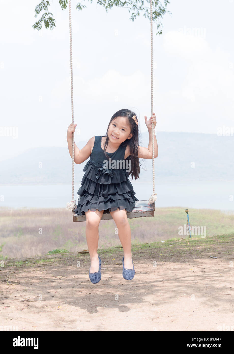 cute girl smile and sit on swing seat on nature background, leisure ...