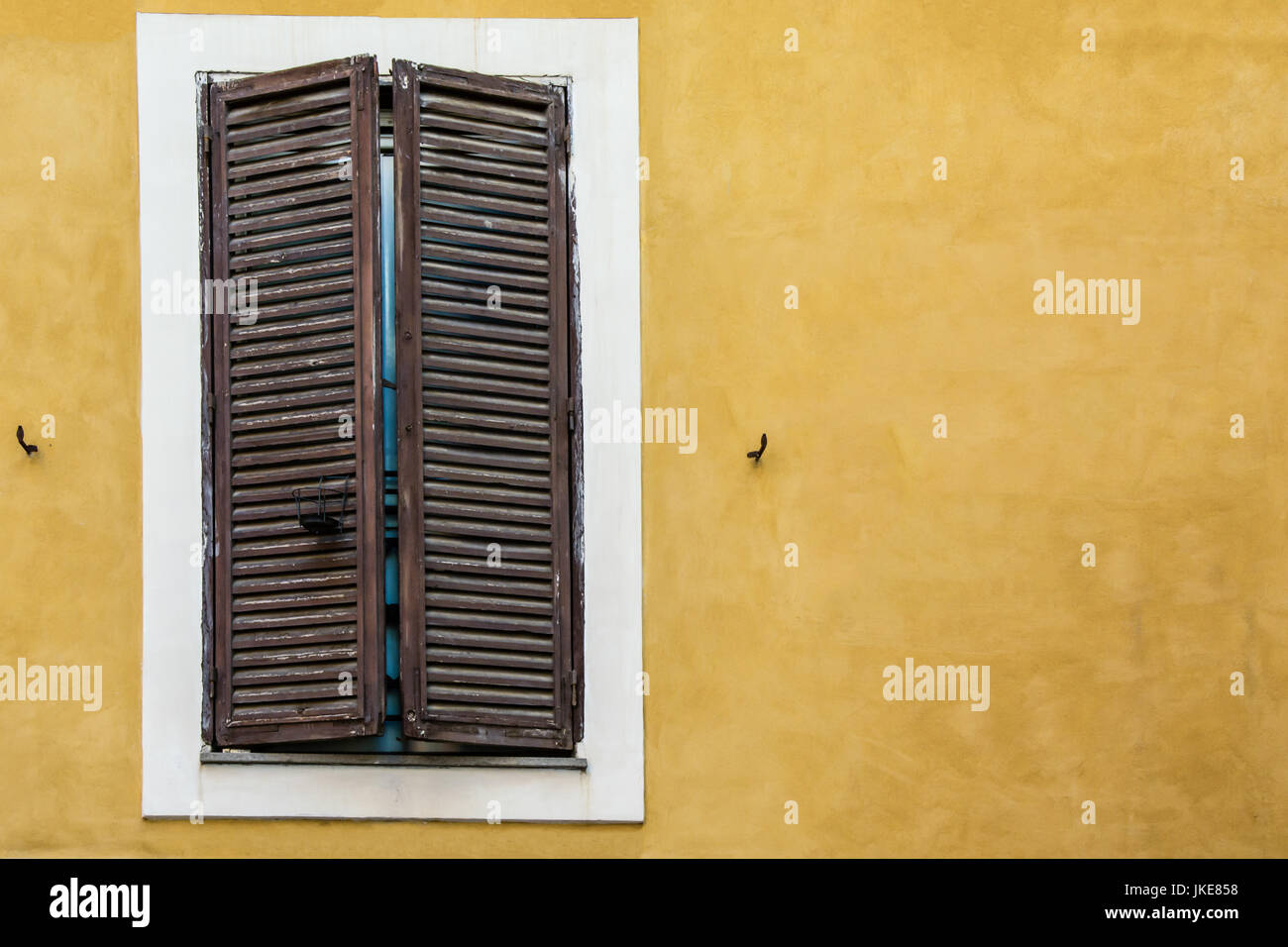 Wooden window with closed shutters and white broad frame on an old ...