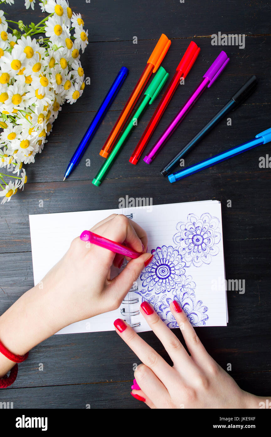 Female drawing flower shapes in a notebook Stock Photo - Alamy