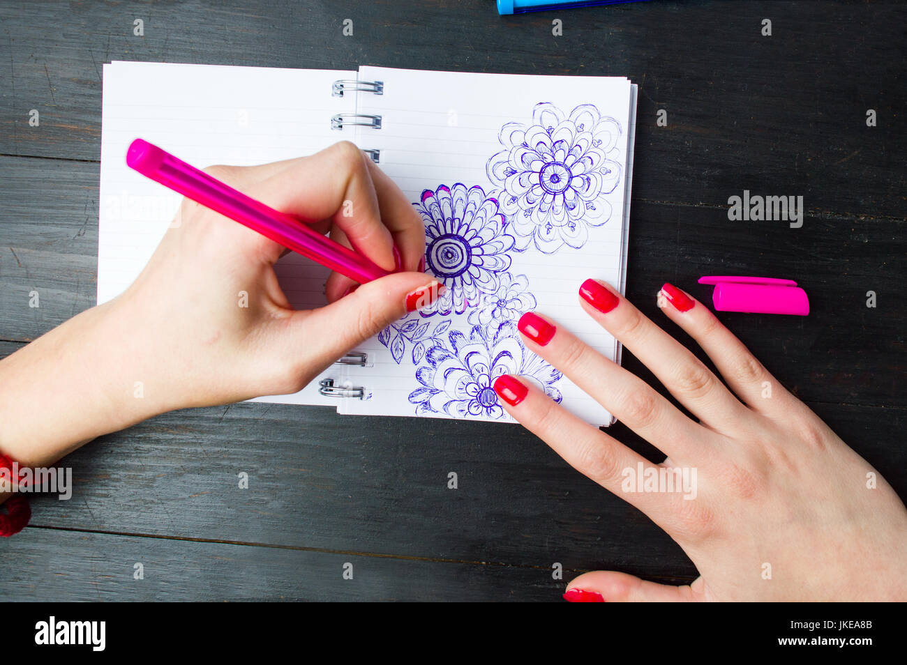 Female drawing flower shapes in a notebook Stock Photo - Alamy