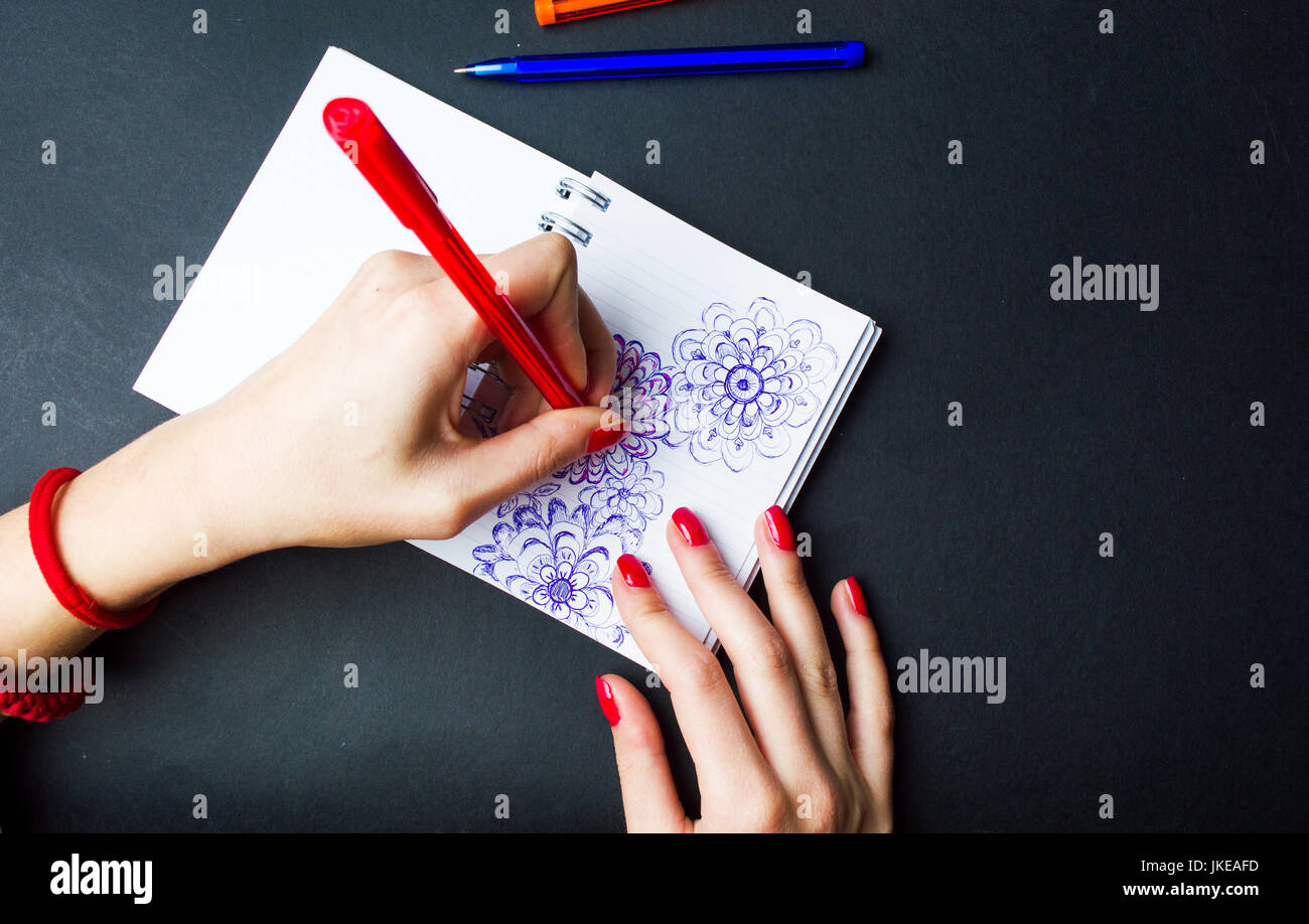 Female drawing flower shapes in a notebook Stock Photo - Alamy