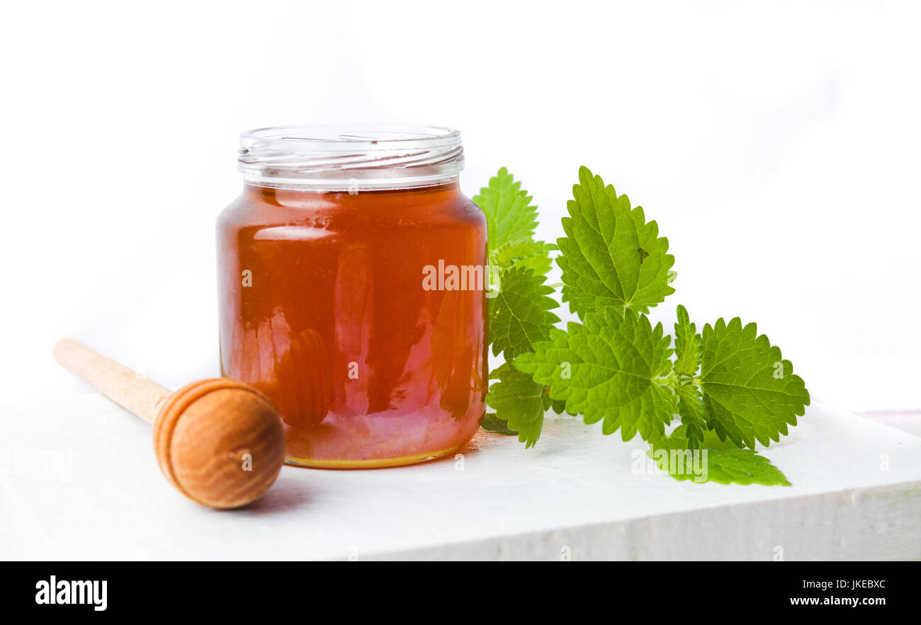 Honey jar and stinging nettle leaves isolated Stock Photo - Alamy