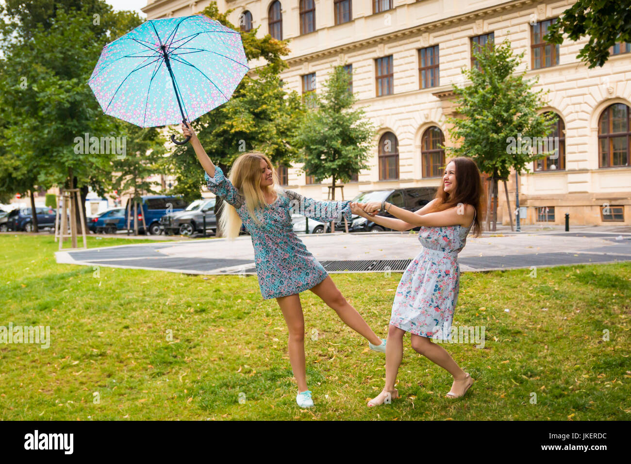Two young best friends having funny crazy time together with umbrella ...