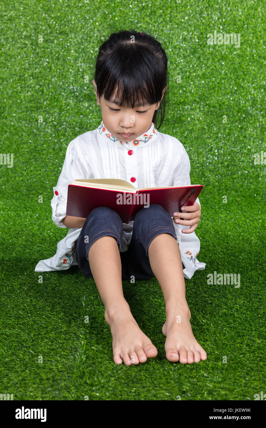 Asian Chinese little girl reading a book on green grass Stock Photo - Alamy