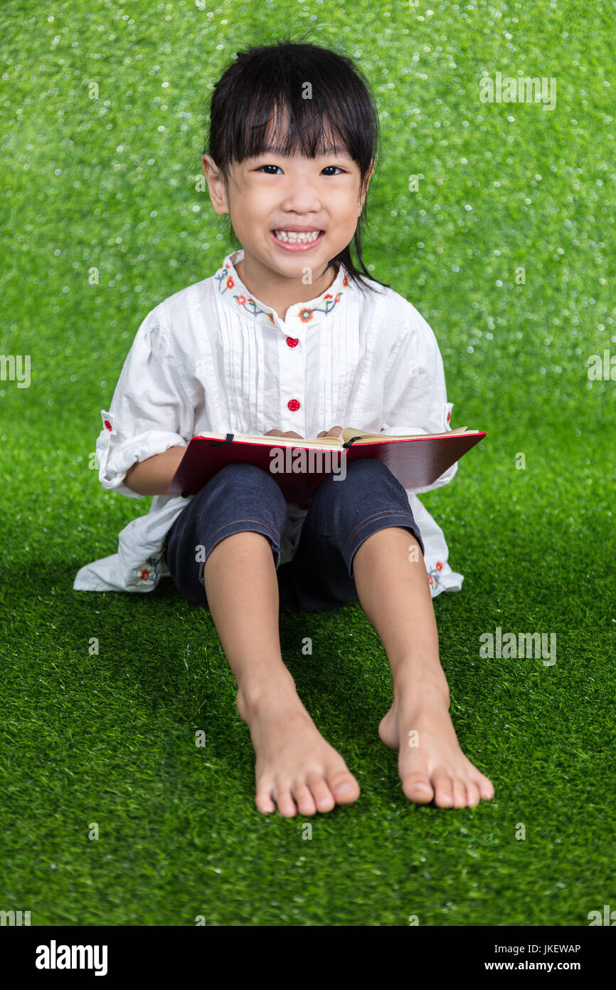 Asian Chinese little girl reading a book on green grass Stock Photo - Alamy