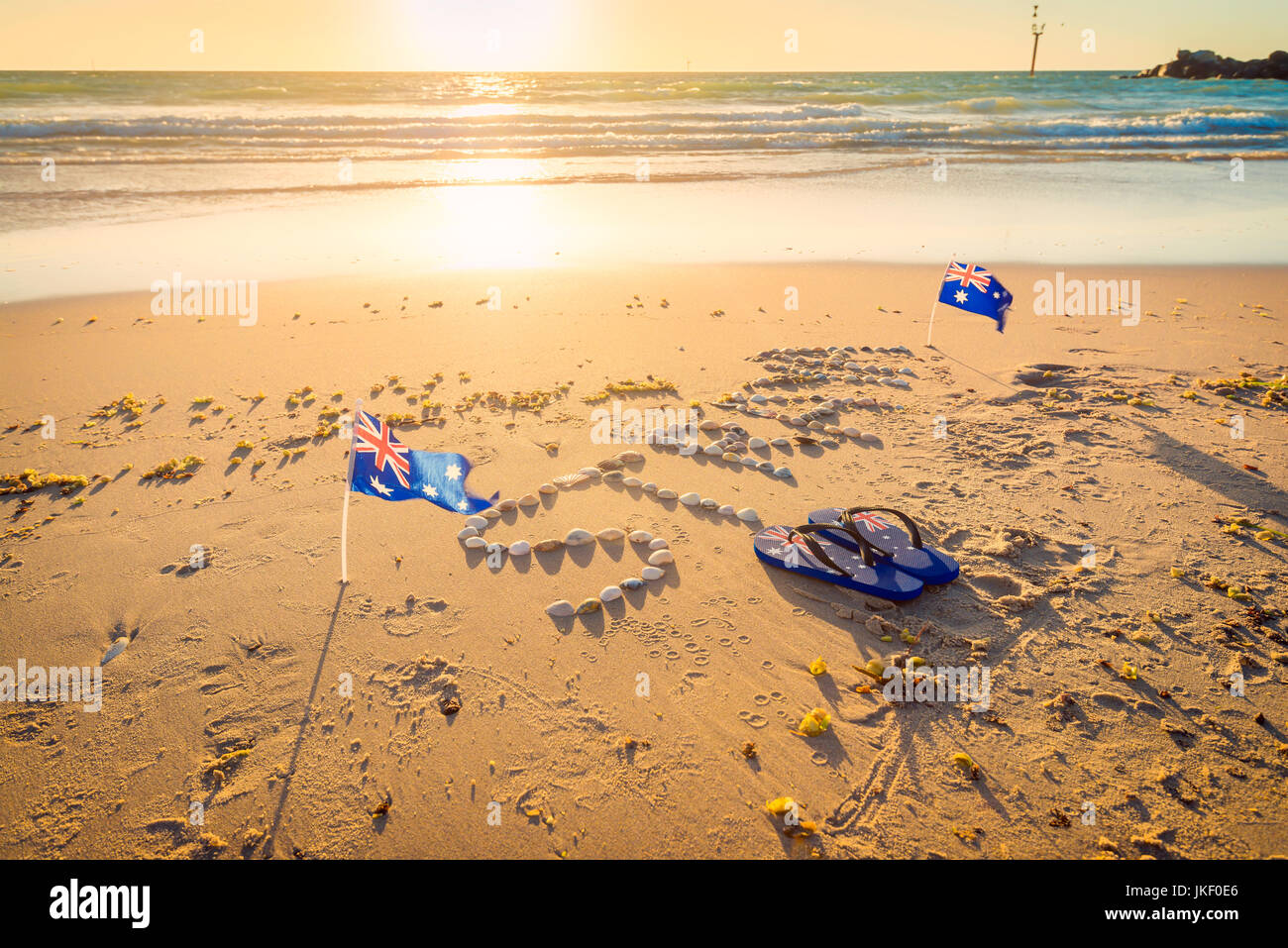 Straya text drawn using shells on sand with flags and thongs. Straya is ...