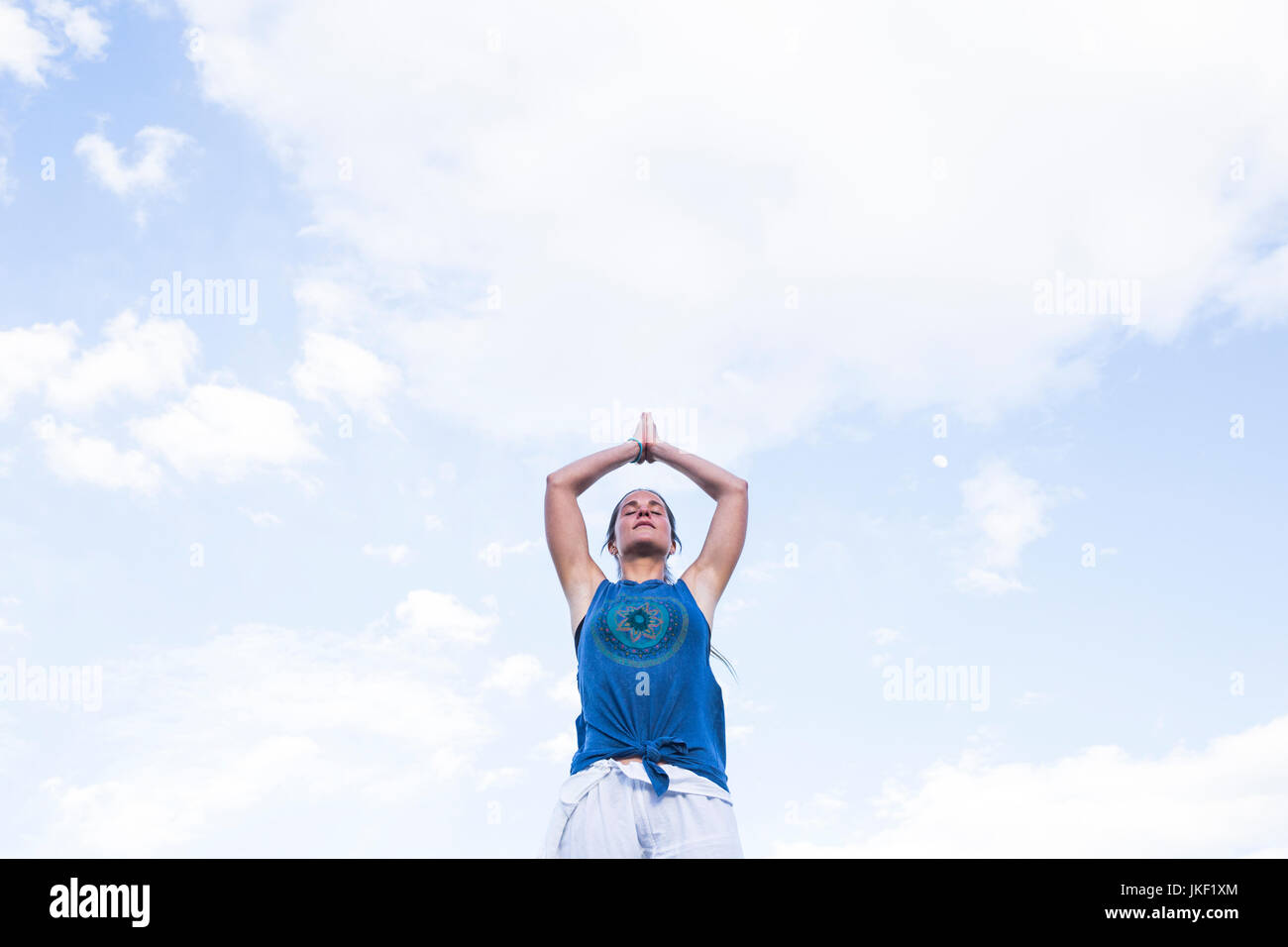 Woman doing a yoga exercise under sky with clouds Stock Photo - Alamy