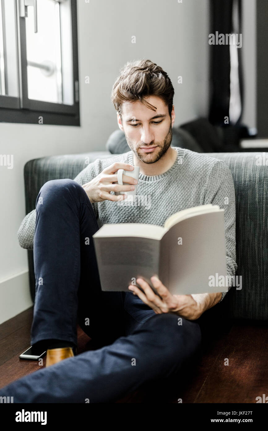 Young man reading book at home Stock Photo - Alamy