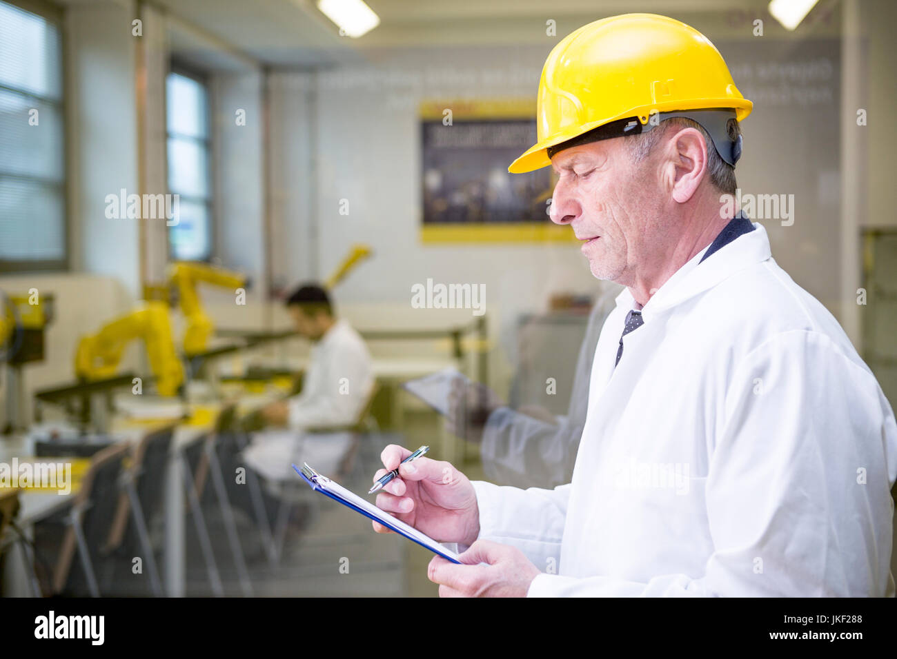 Engineer in factory with clipboard Stock Photo - Alamy