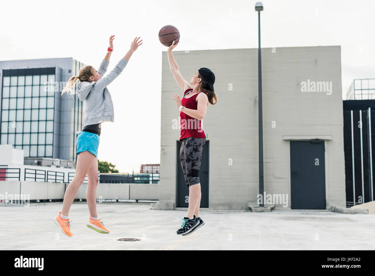 Two women playing basketball on parking level in the city Stock Photo ...
