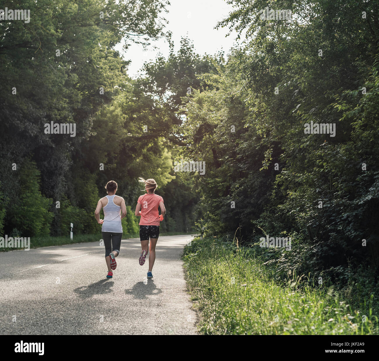 Two women running on country road Stock Photo - Alamy