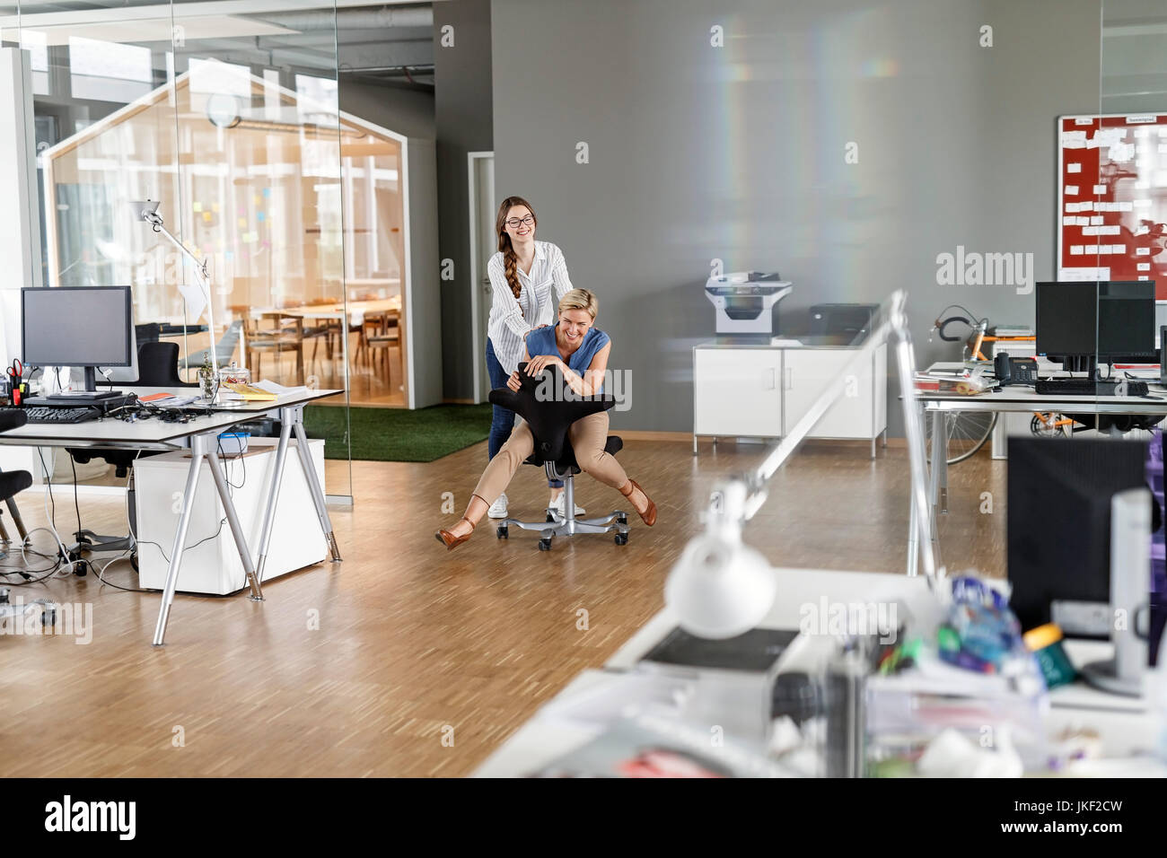 Playful employee pushing colleague on office chair Stock Photo - Alamy