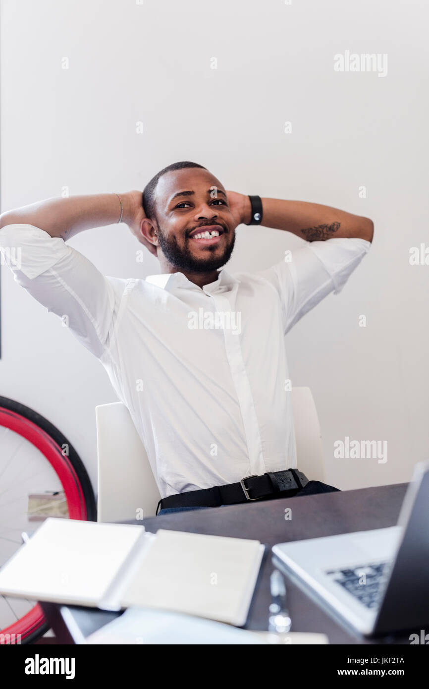 Relaxed businessman at desk leaning back Stock Photo - Alamy