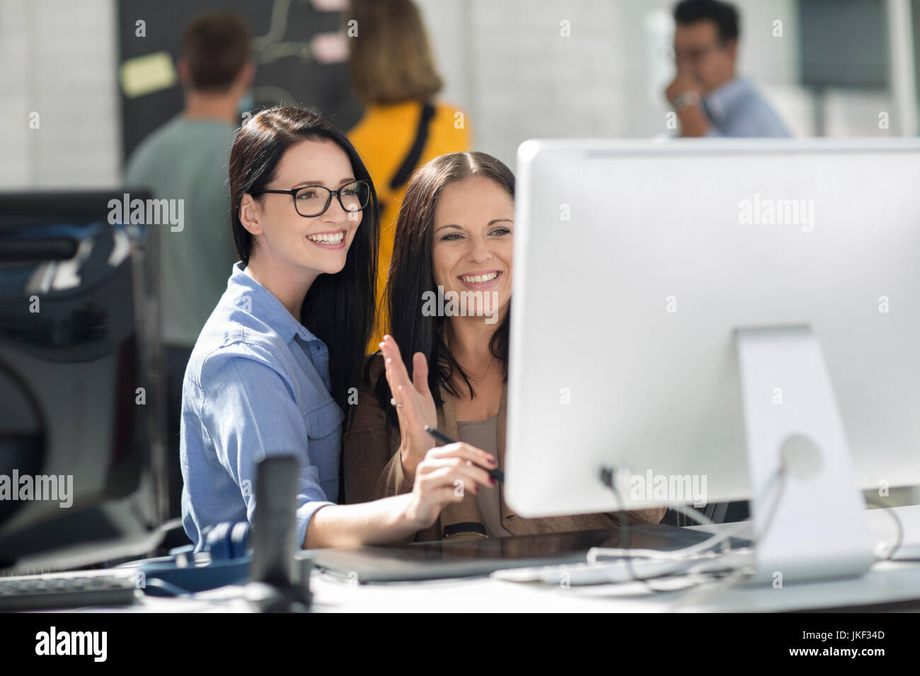 Two colleagues laughing and working on computer Stock Photo - Alamy