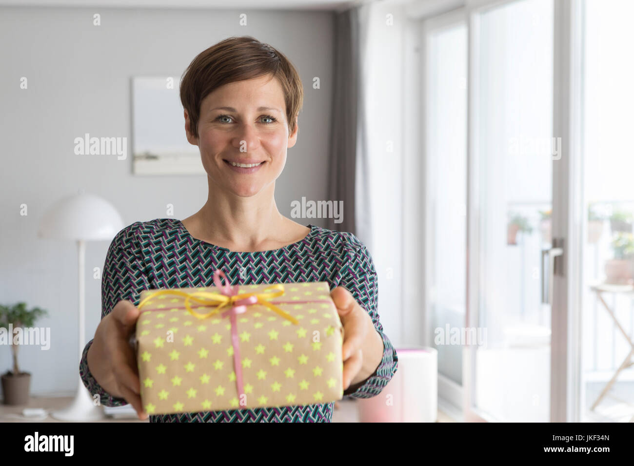 Portrait of smiling woman presenting gift Stock Photo - Alamy