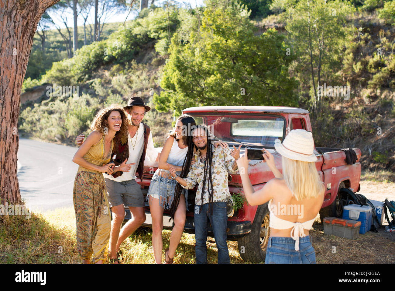 Young woman taking cell phone picture of friends outside pick up truck ...