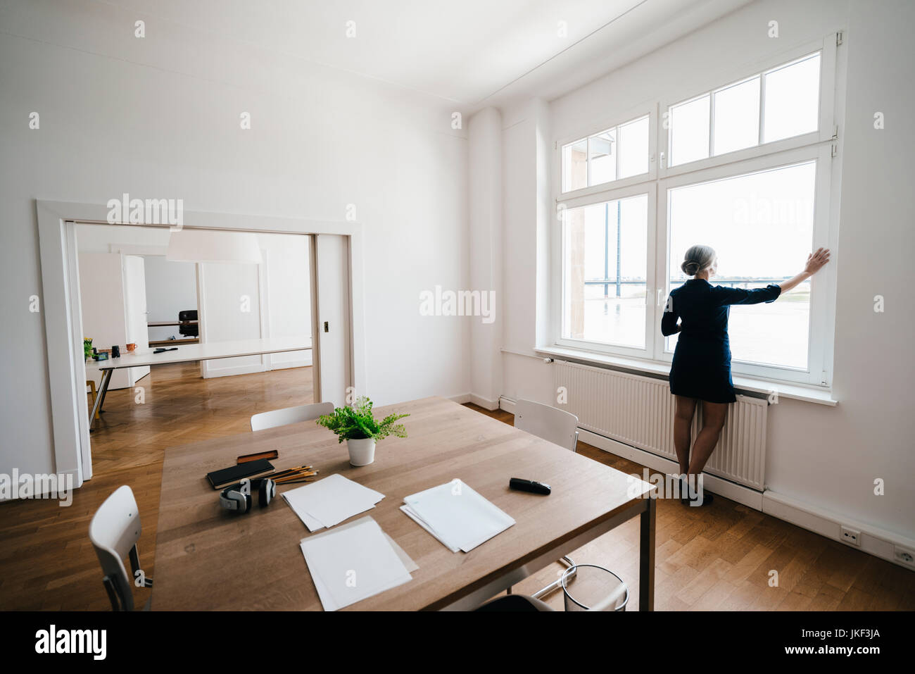 Businesswoman in office looking out of window Stock Photo - Alamy