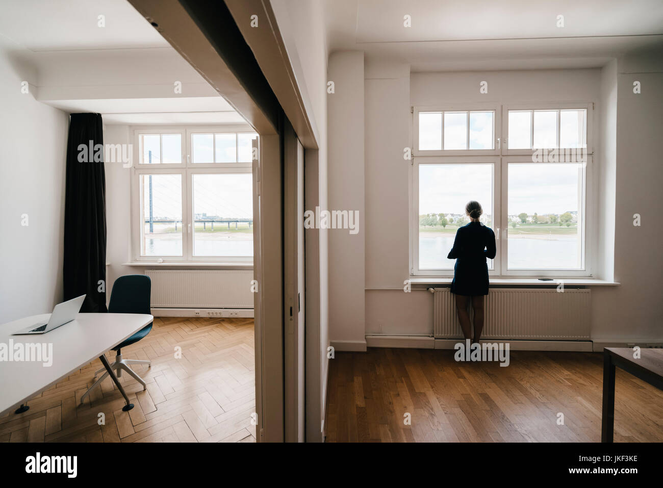 Businesswoman in office looking out of window Stock Photo - Alamy