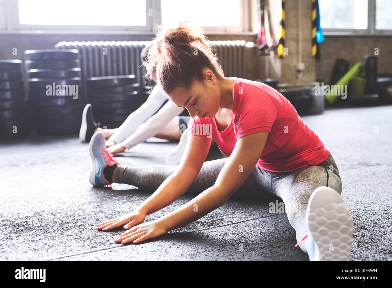 Two young people stretching in gym Stock Photo - Alamy