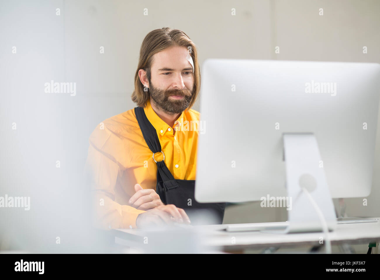 Employee focusing on his work wearing a sling Stock Photo - Alamy