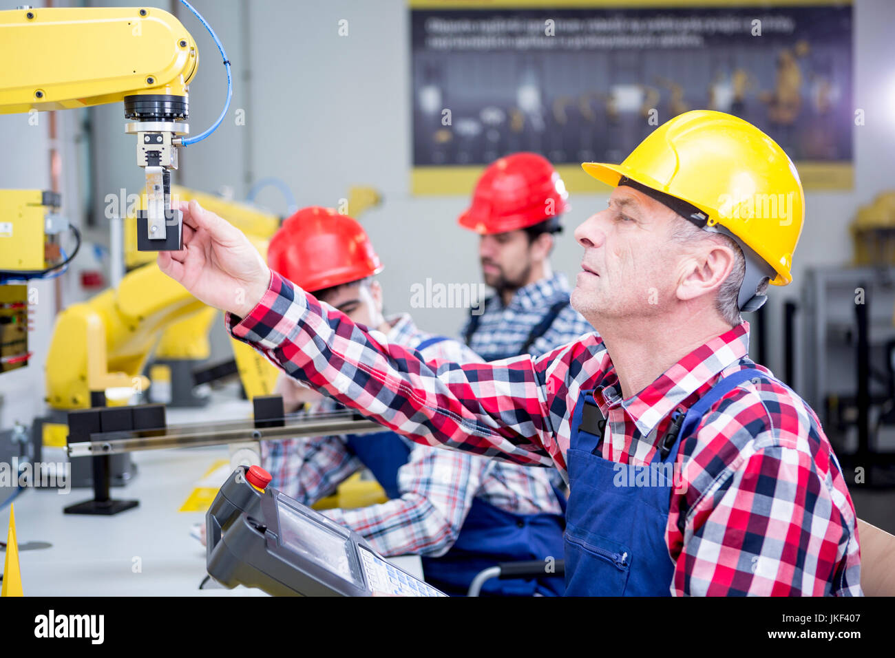 Man wearing hard hat adjusting industrial robot Stock Photo - Alamy