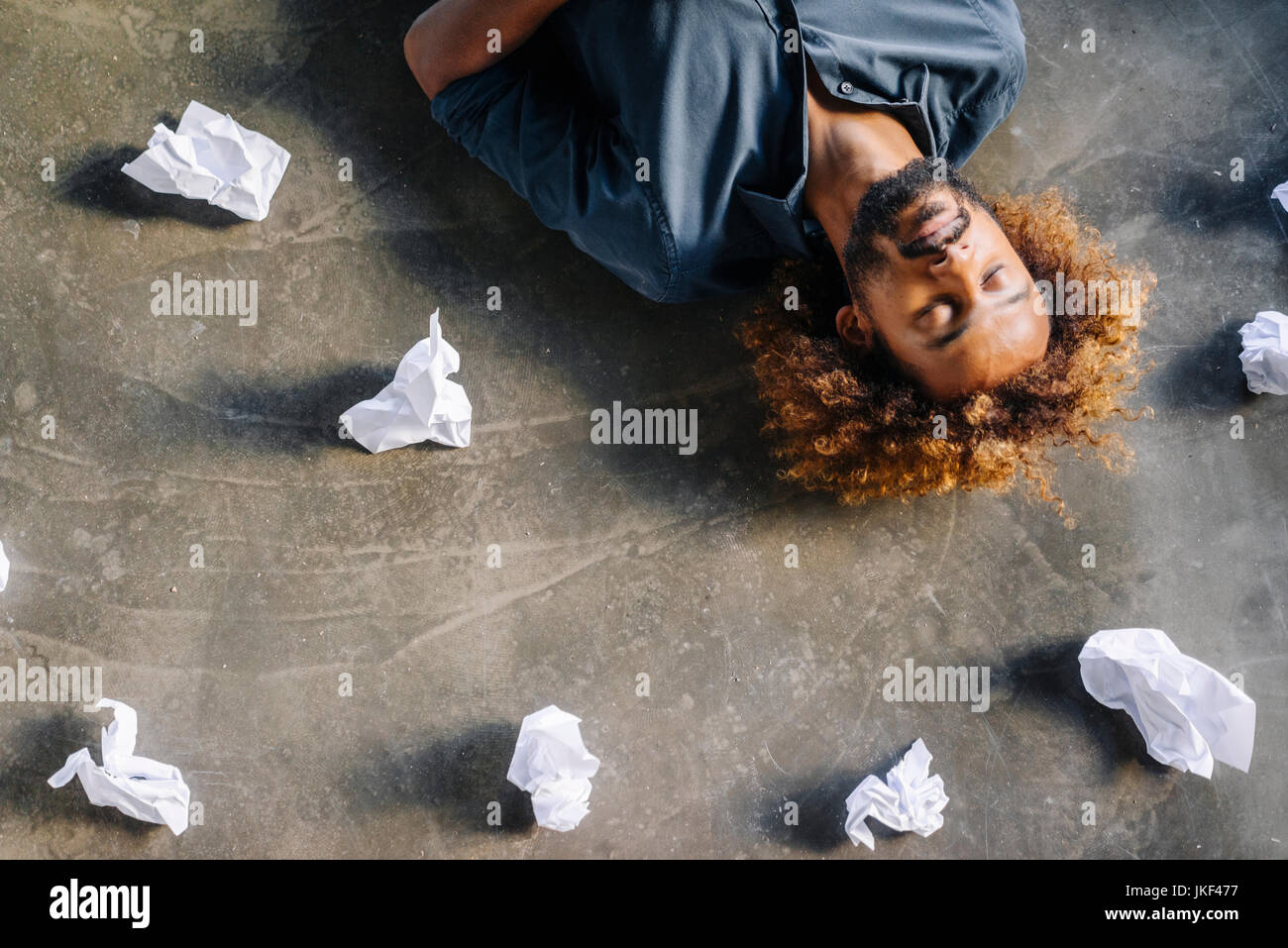 Man lying on the floor surrounded by crumpled paper Stock Photo - Alamy
