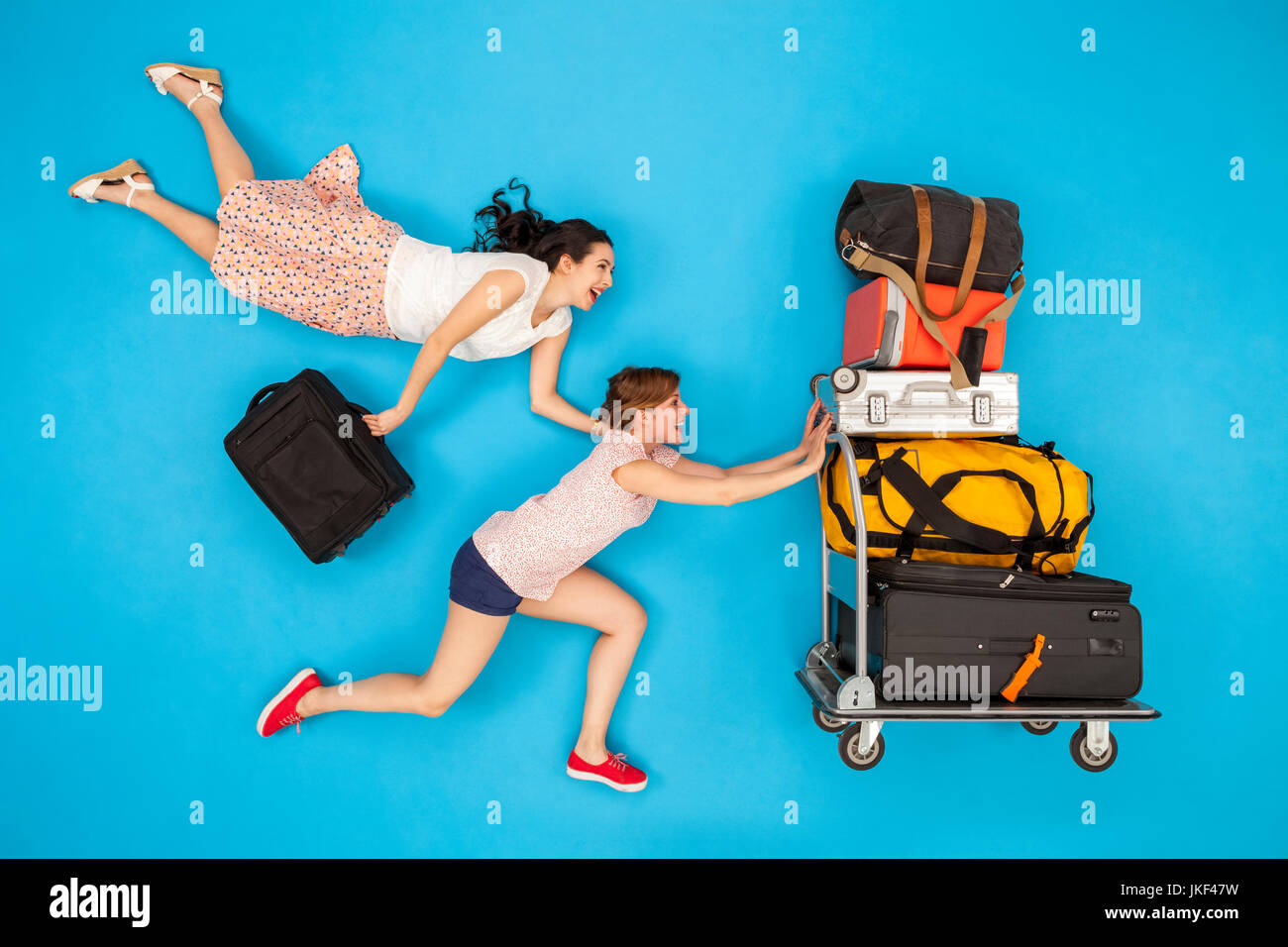 Friends pushing luggage trolley, hurrying for departure Stock Photo - Alamy