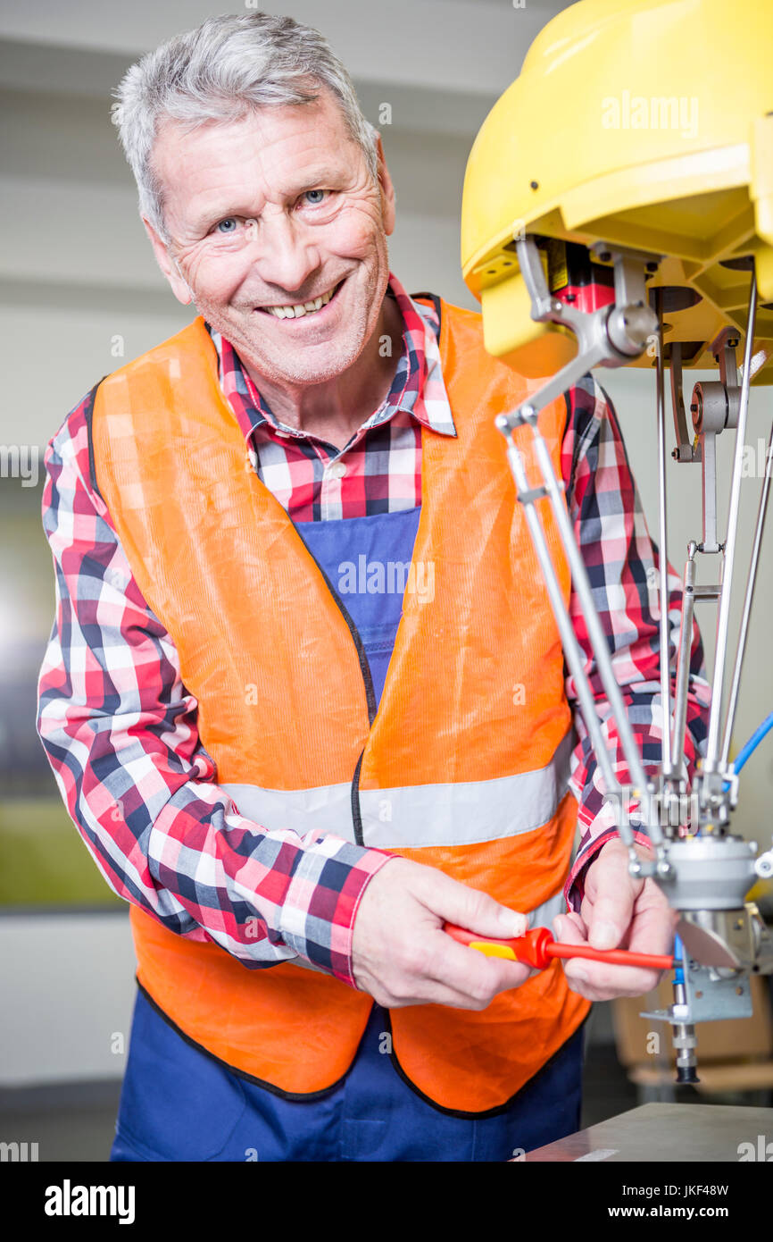 Portrait of smiling technician adjusting industrial robot Stock Photo ...