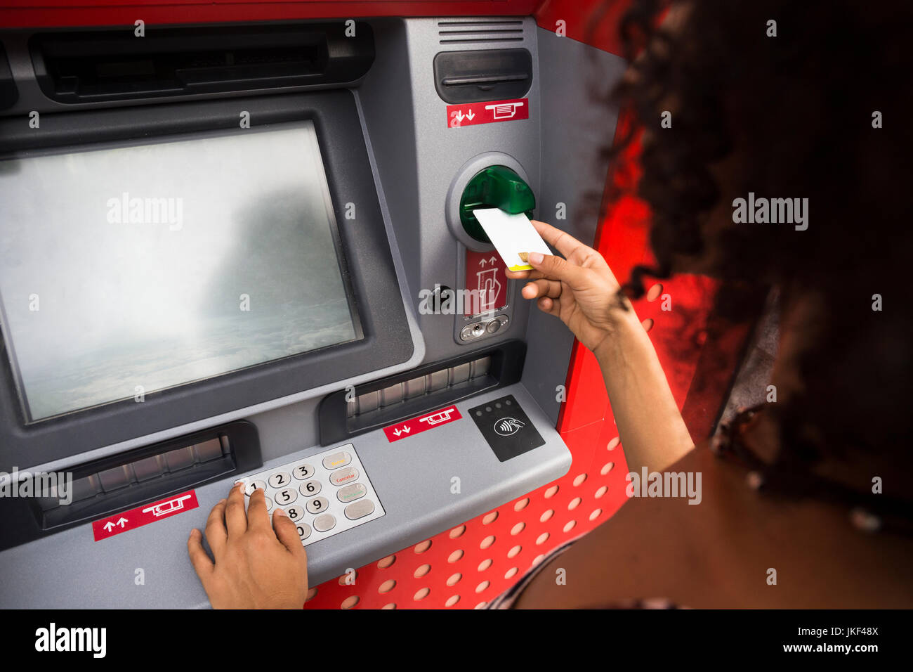 Woman pushing credit card at cash dispenser Stock Photo - Alamy